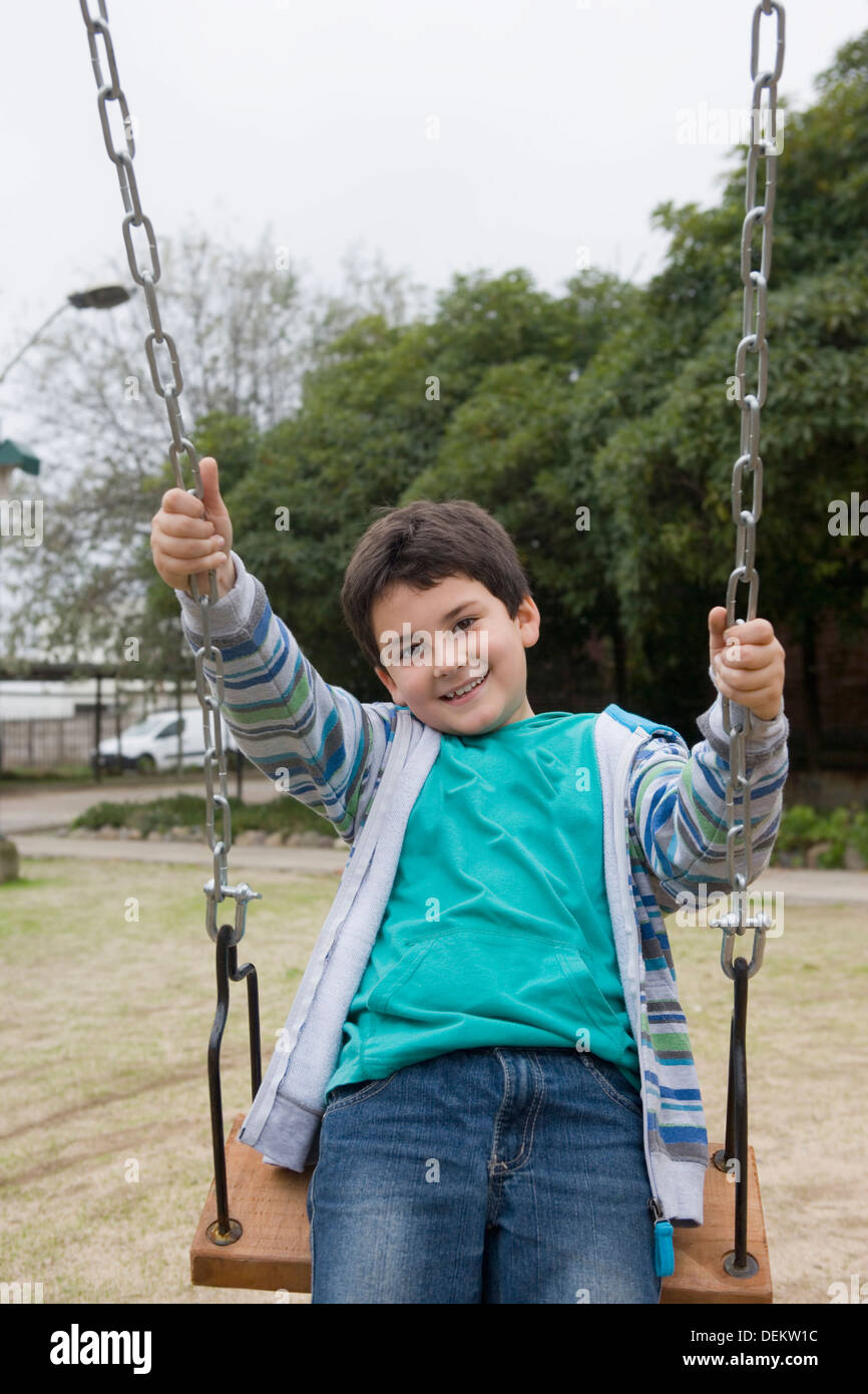 Hispanic boy playing on swing Stock Photo - Alamy