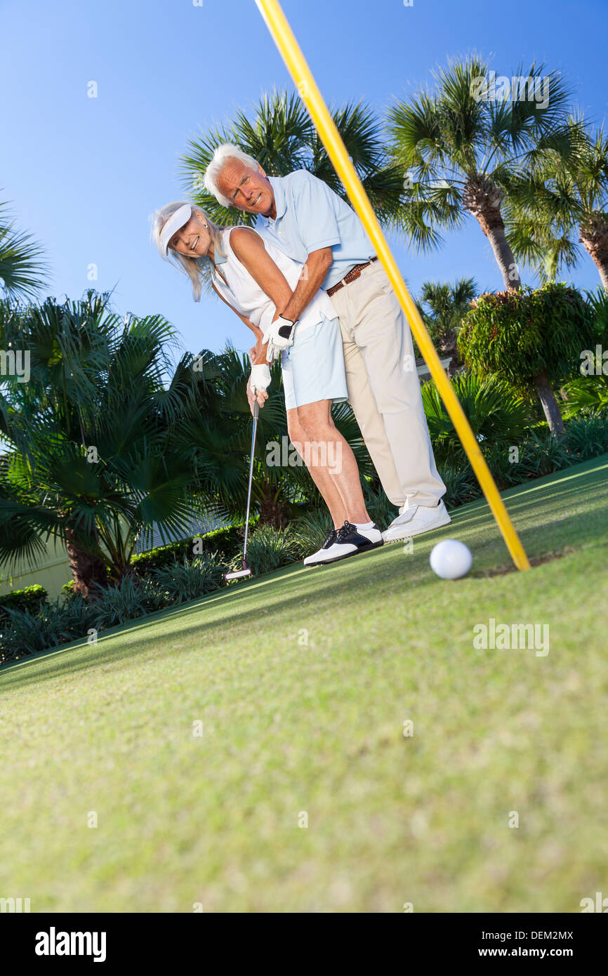 Happy senior man and woman couple together playing golf and putting on ...