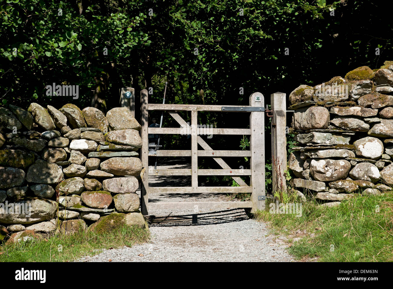 Wooden gate set in dry stone wall across public footpath path in summer ...