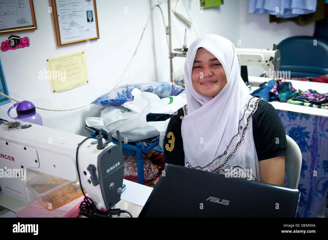 Happy young Muslim woman at work as a seamstress, Labuan, Malaysia ...