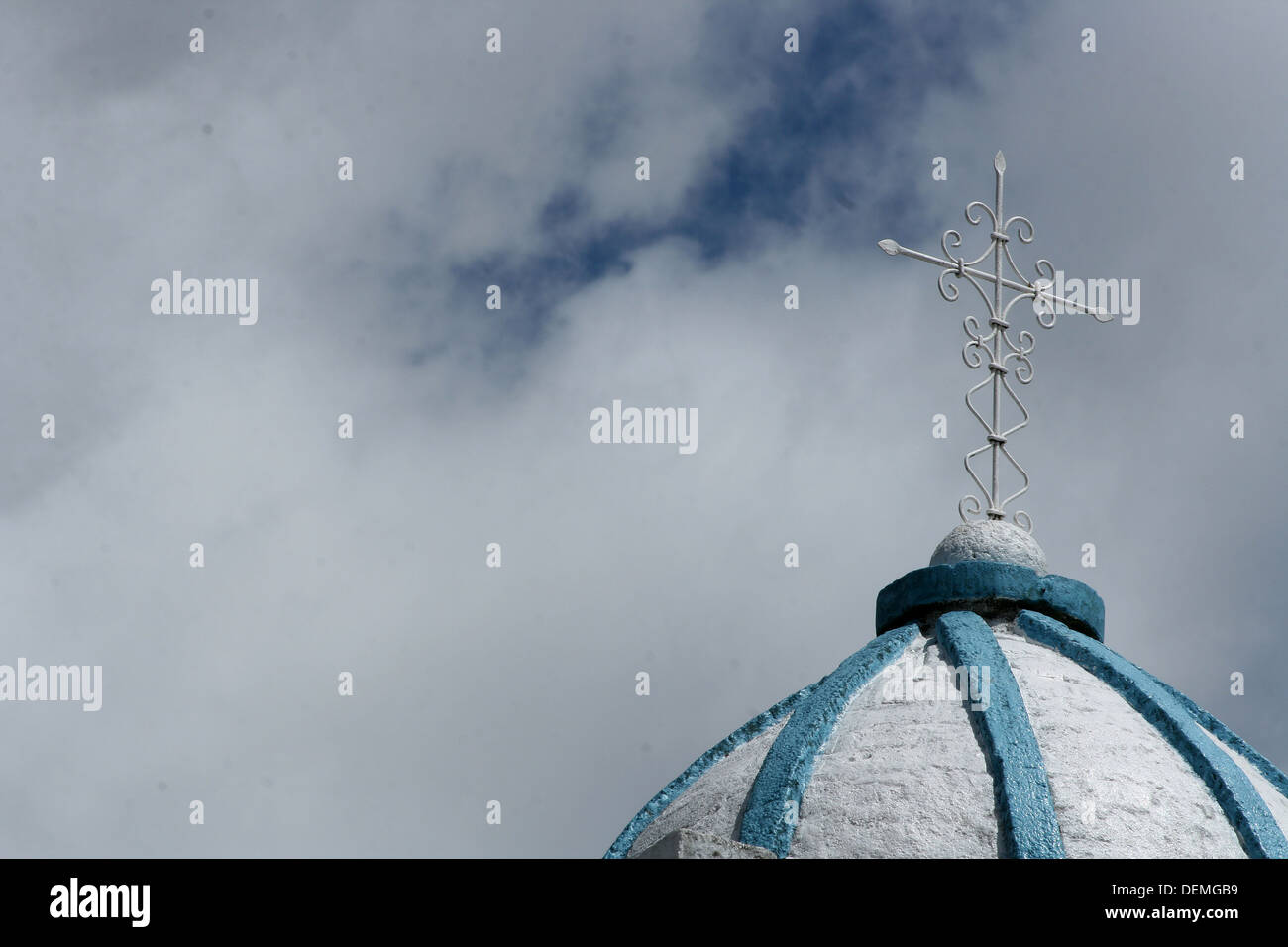 A painted steel cross on the dome of a small Catholic church near ...