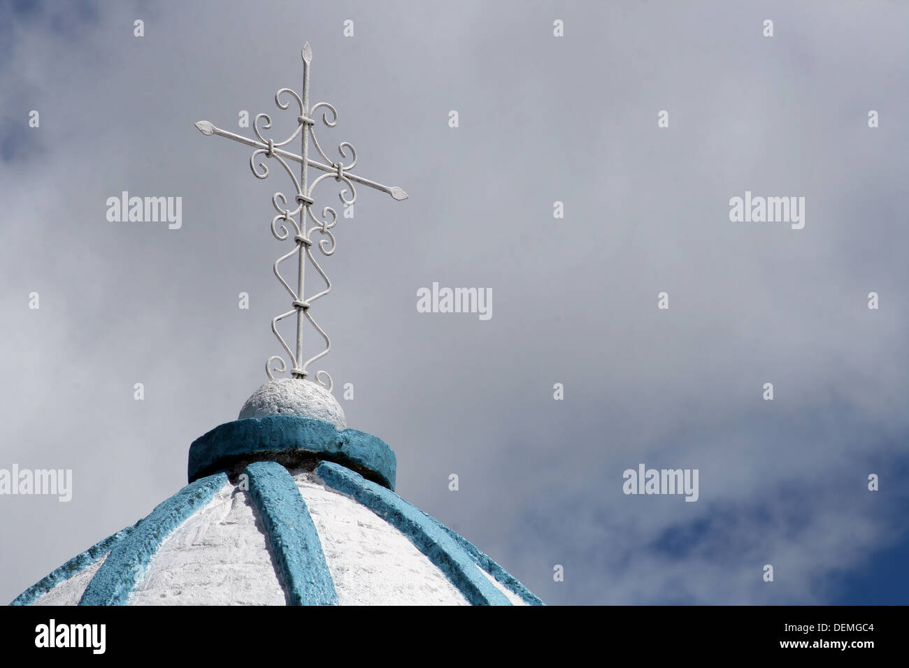 A painted steel cross on the dome of a small Catholic church near ...