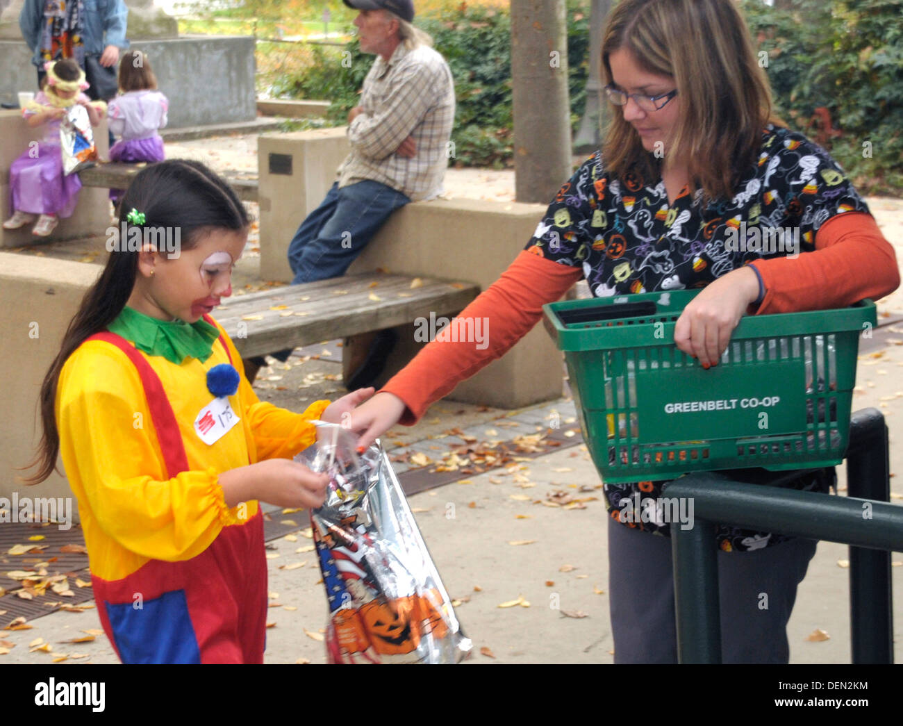 Little girl receives candy from a store employee during a trick or ...