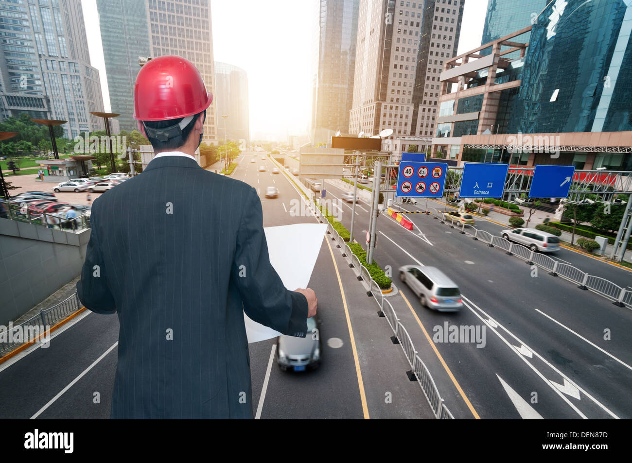 Rear view of architect looking comparing housing project with building ...