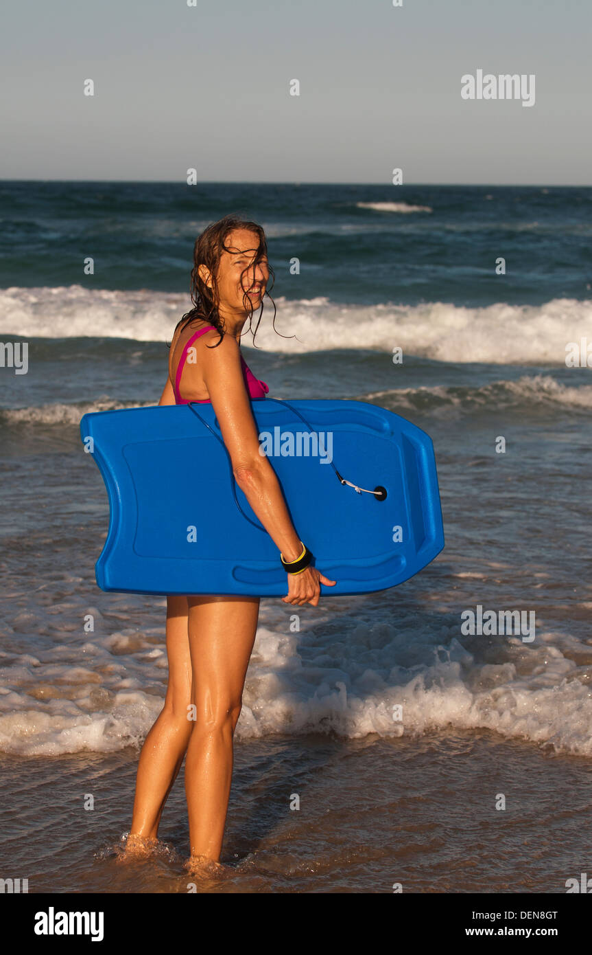 Mature fit healthy woman boogey (or body) boarding in the surf at the ...