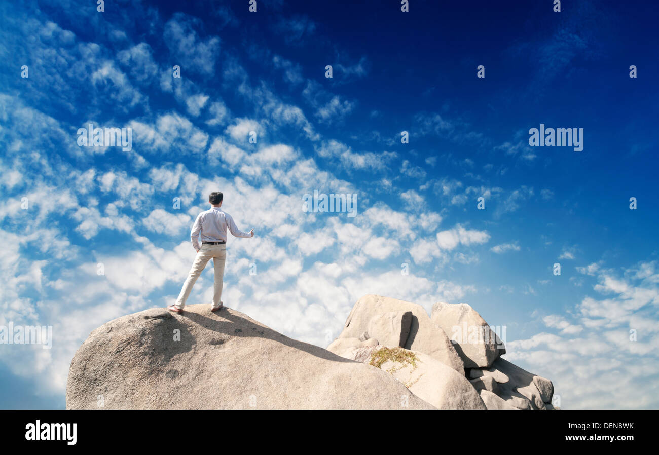 Young man standing on cliff's edge and looking into a wide valley Stock ...