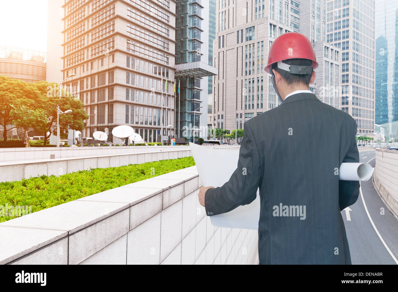 Rear view of architect looking comparing housing project with building ...