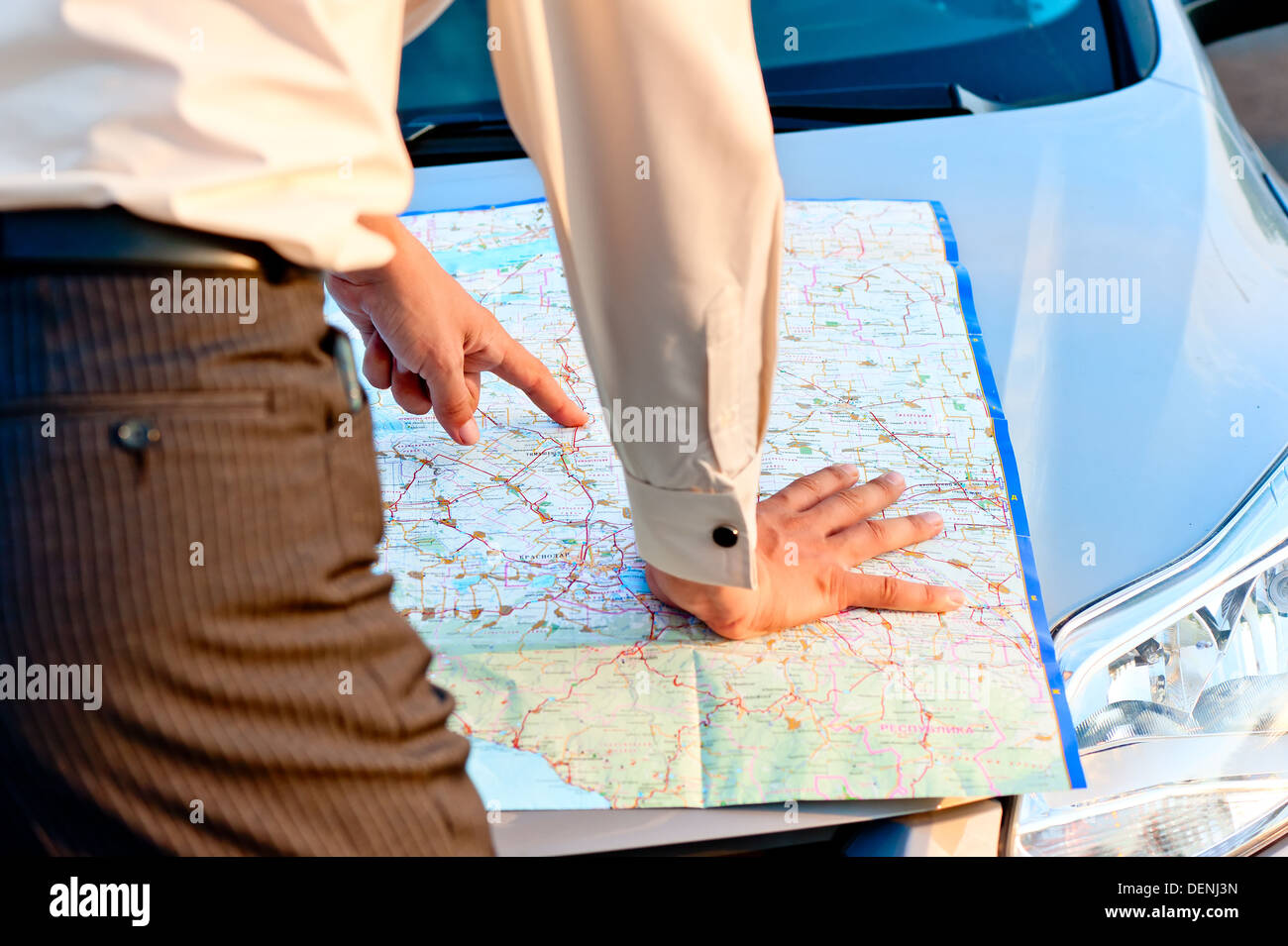 Businessman looking at a map spread out on the hood of a car Stock ...