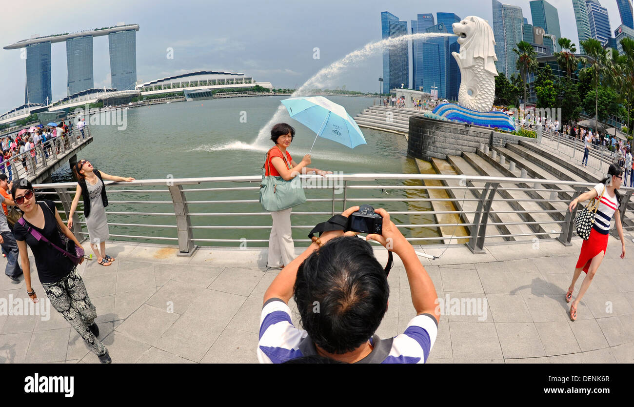 Tourist posing for photographs at the Merlion park in Singapore Stock ...