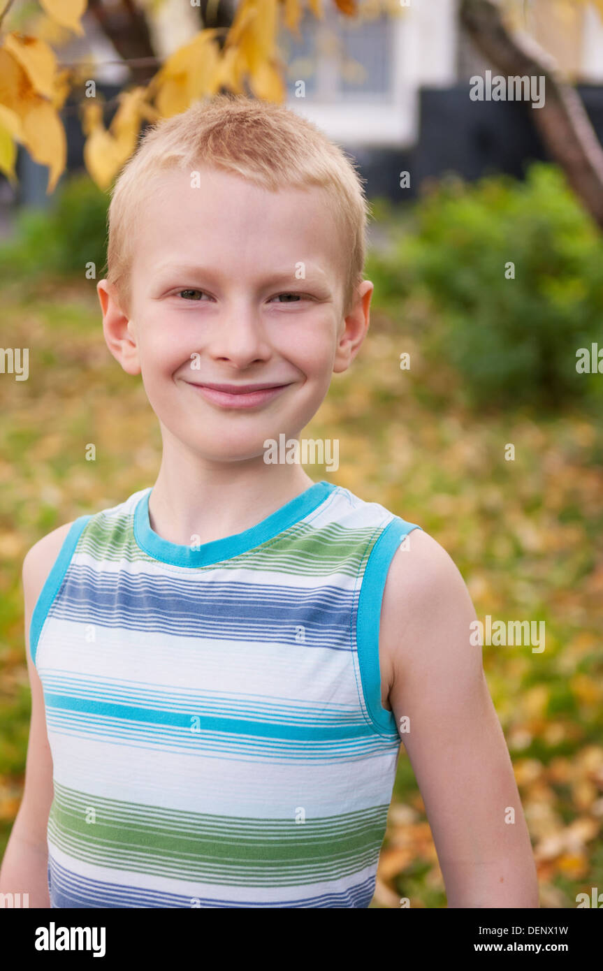 Adorable boy smiling, fall leaves and school building on background ...
