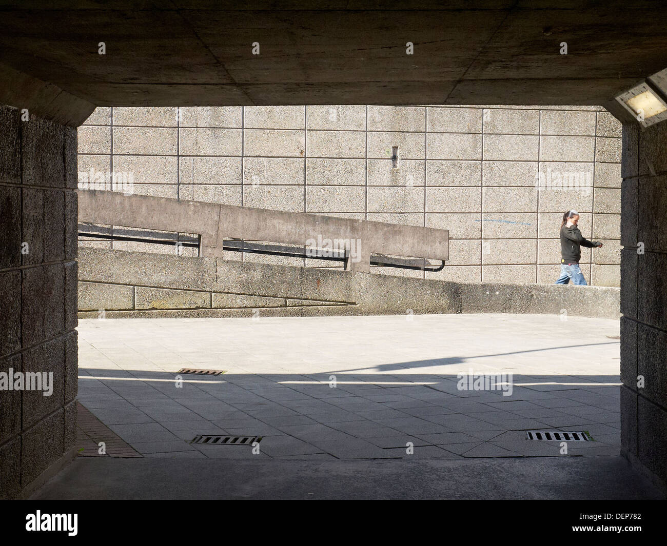 Woman walking in depressing architecture as seen from underpass in ...