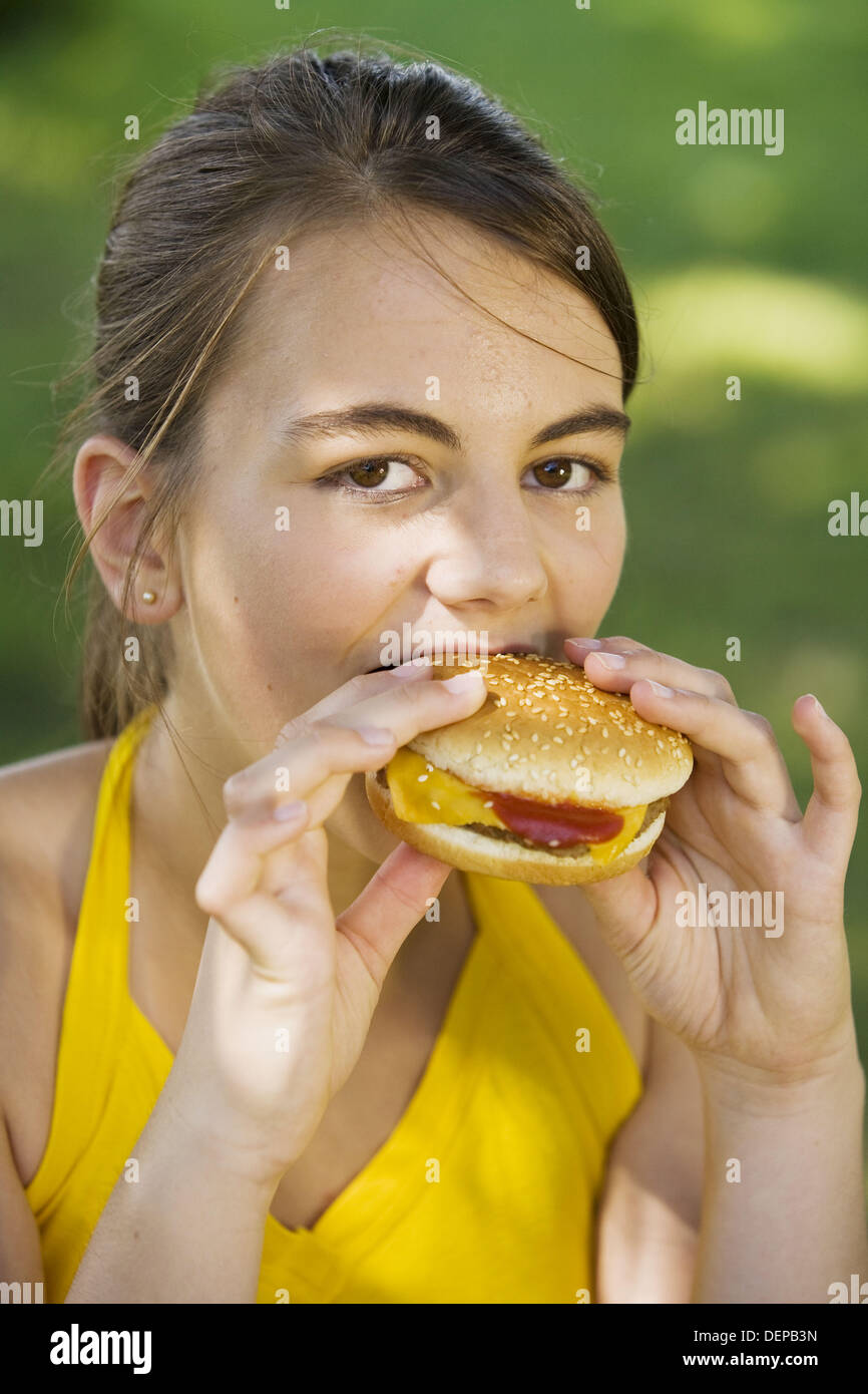 Teenaged girl biting into a hamburger outdoors Stock Photo - Alamy