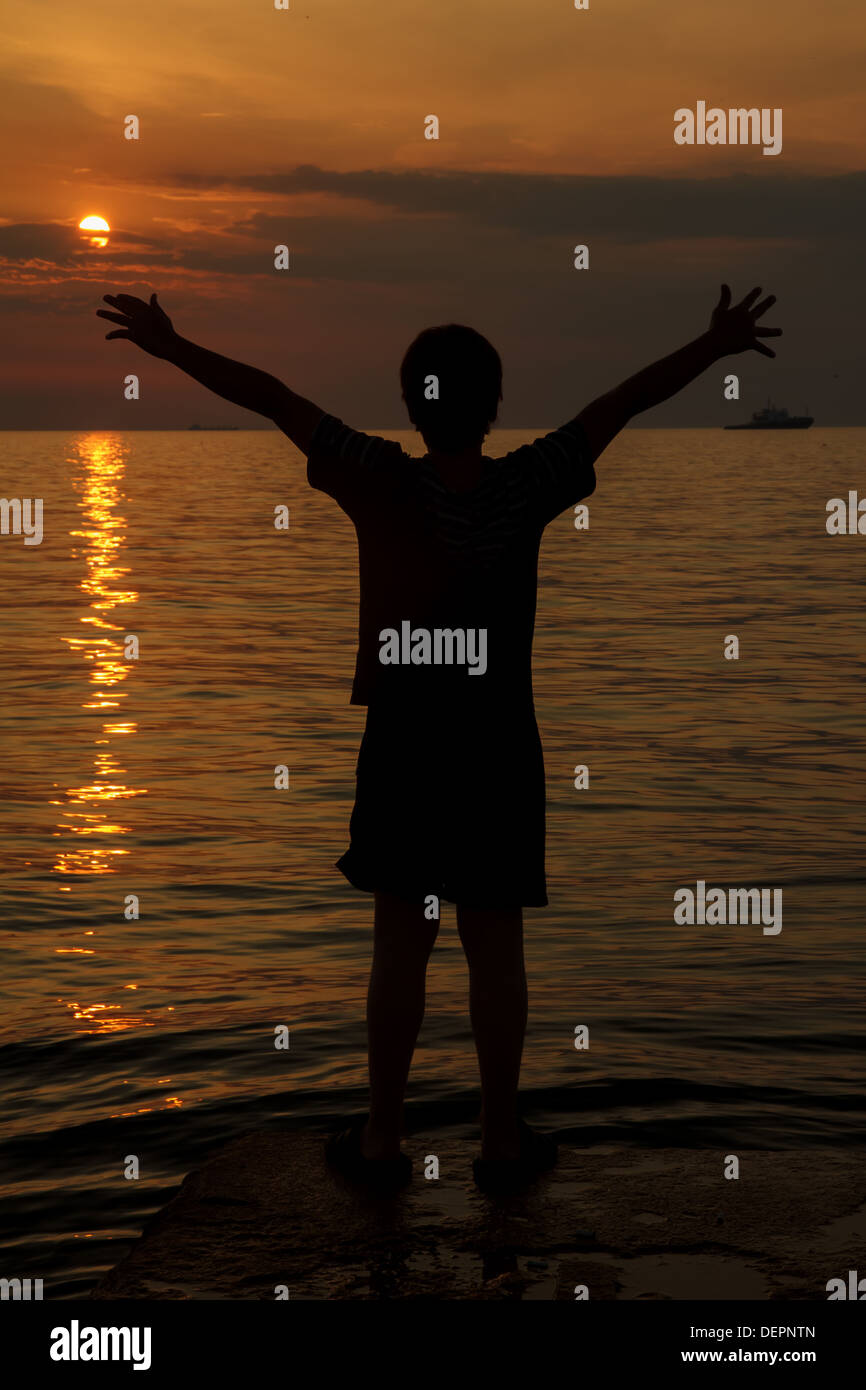 boy with his hands raised in the sunset over the sea Stock Photo - Alamy
