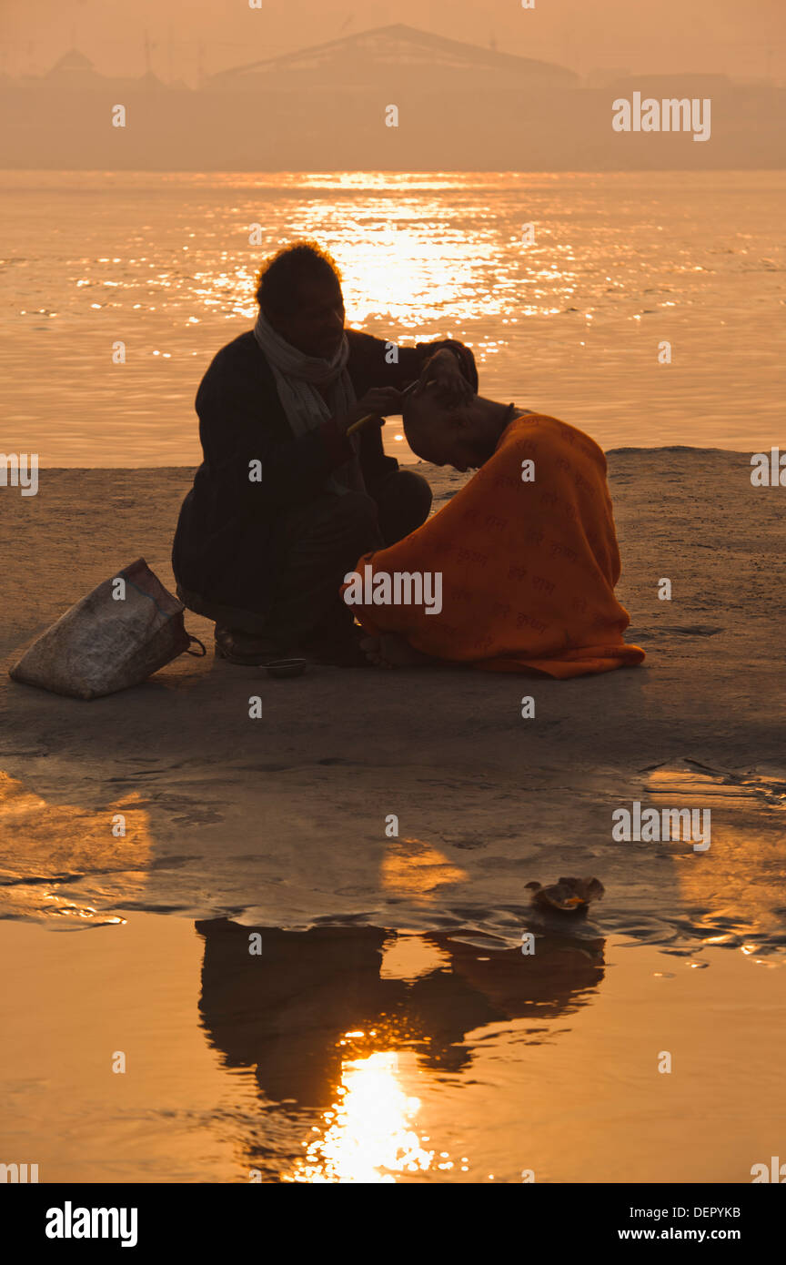 Barber shaving head of a man on the bank of Ganges River at Maha Kumbh ...