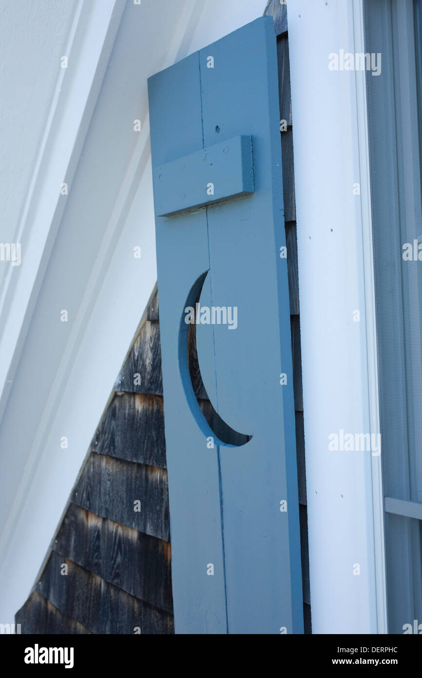 A cutout crescent moon decorates a window shutter on a Cape Cod home ...