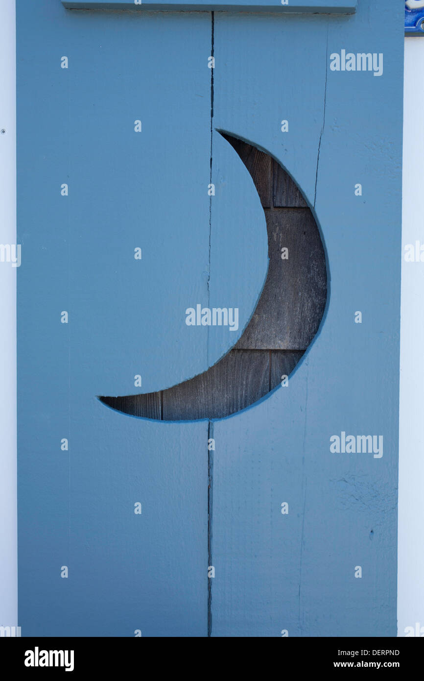 A cutout crescent moon decorates a window shutter on a Cape Cod home ...