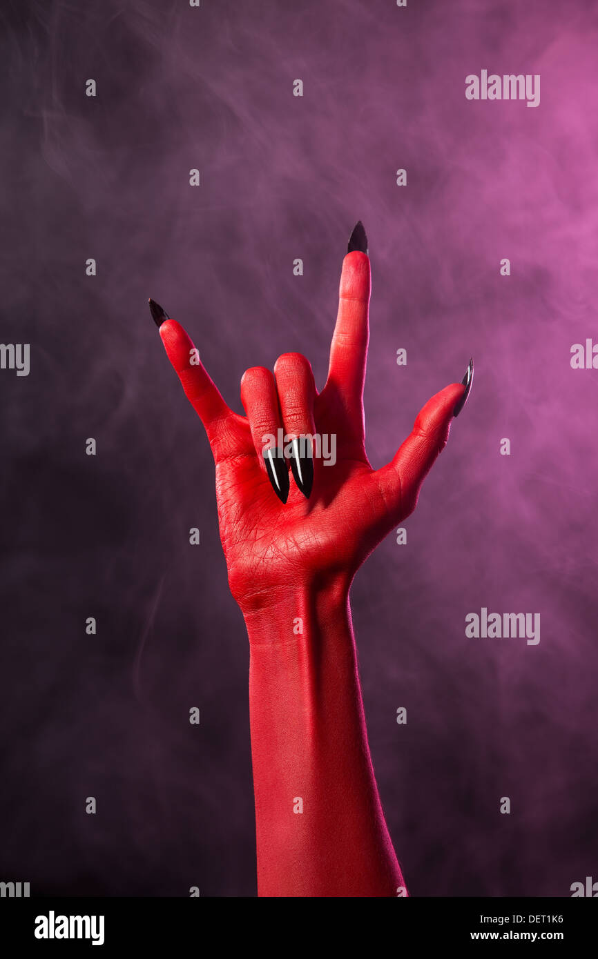 Rock sign, red devil hand with black nails, Halloween Stock Photo - Alamy
