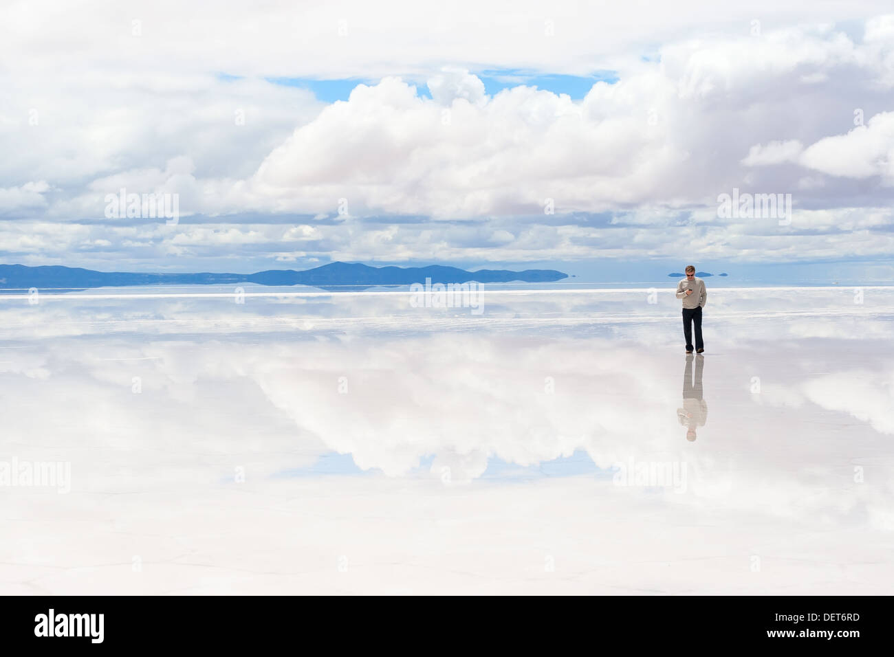 Man working on the mobile phone in the middle of lake Salar de Uyuni ...