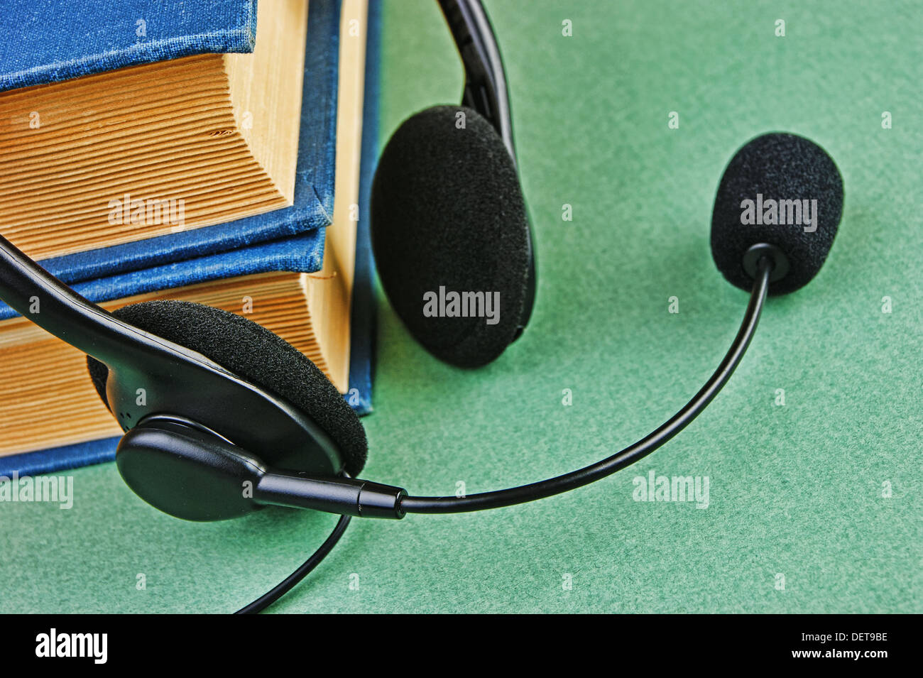 Headphones with a microphone and a stack of books on a green background ...