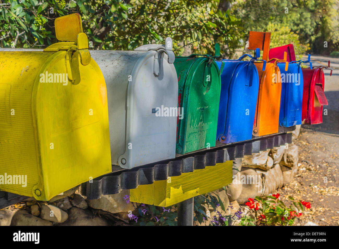 Line of seven brightly colored mailboxes, some with their metal flags ...