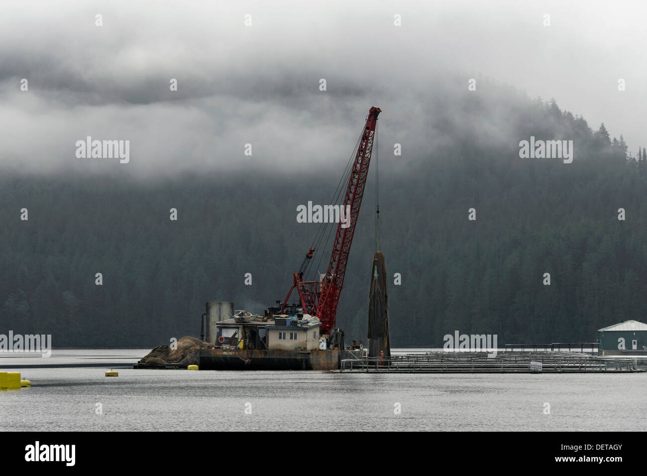 Crane pulling up nets at a salmon farm, Mussel Inlet, mid-coast British ...