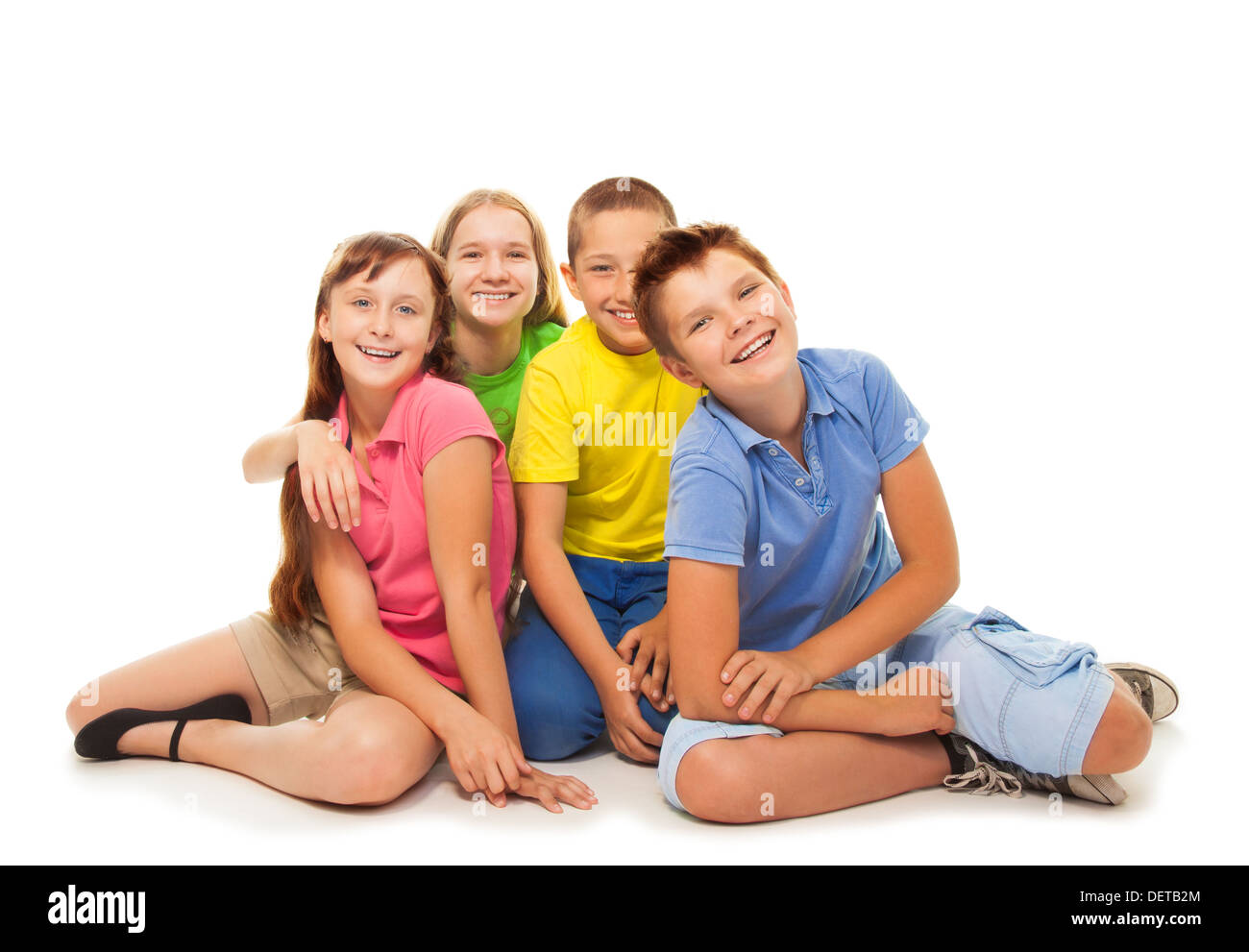 Group of happy boys and girls sitting on the floor isolated on white ...