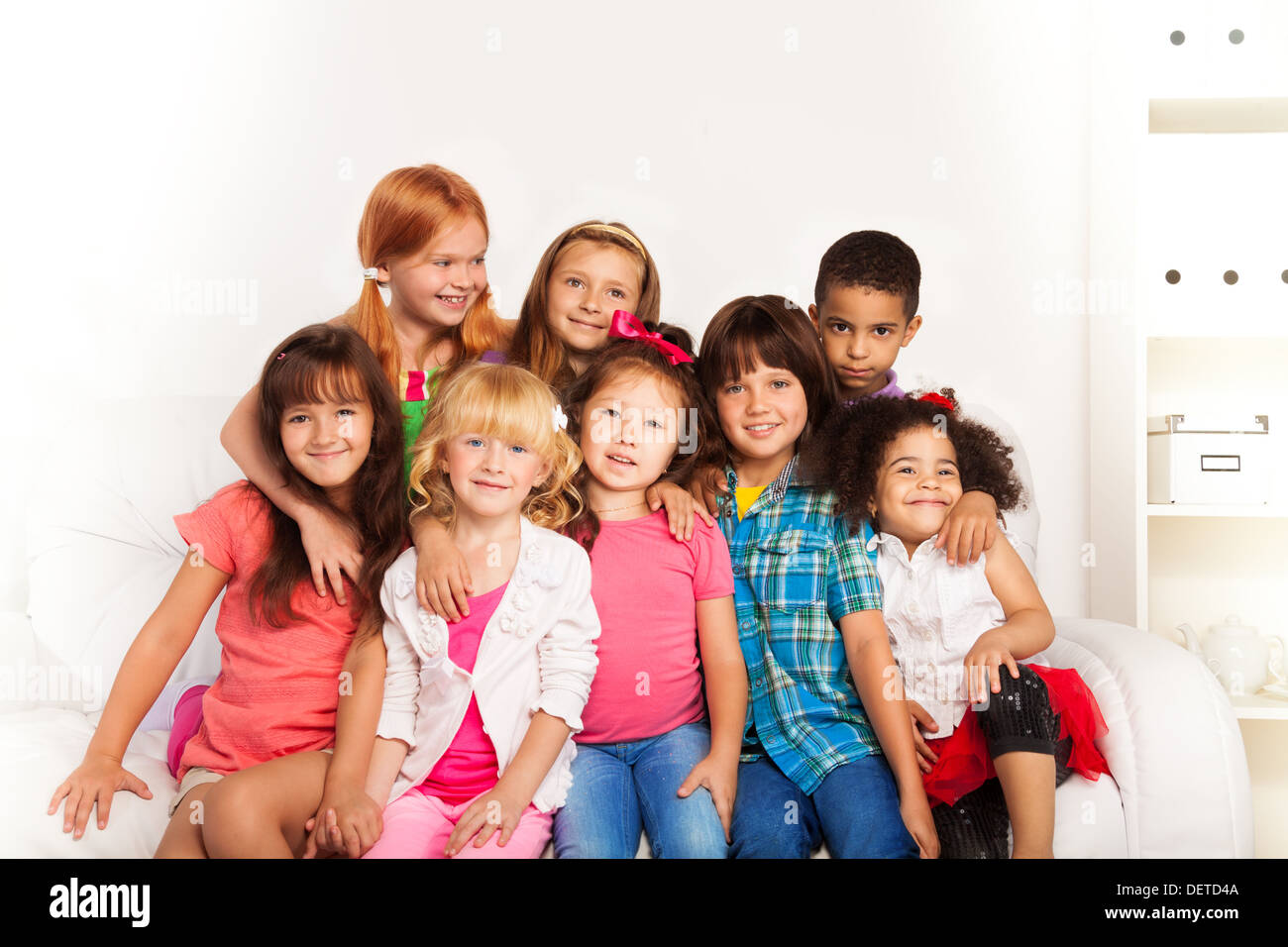 Group of little kids sitting on a couch and smiling, hugging together ...