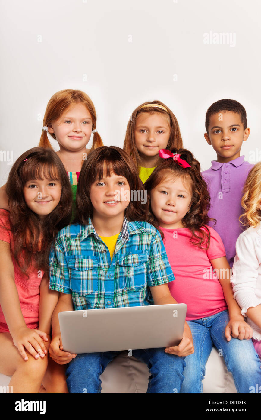 Close portrait of large group of kids sitting with laptop on the coach ...