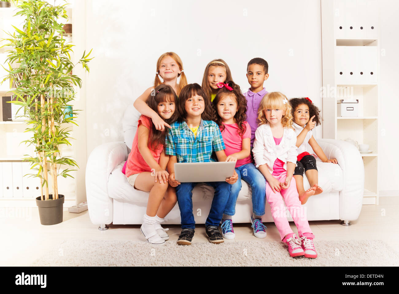 Large group of kids sitting on the couch with laptop, with one girl ...