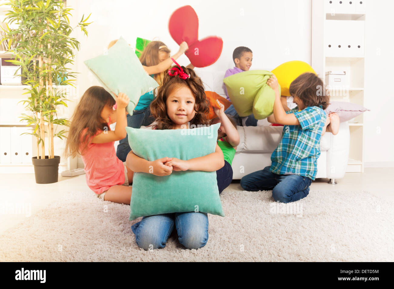 Happy smiling little Asian girl hugging pillow with large group of her ...