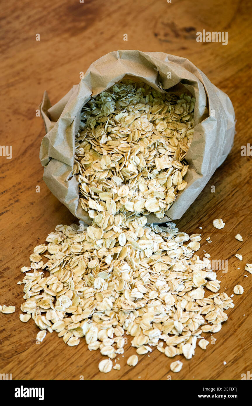 Rolled oats spilling out of a paper bag onto a wood table Stock Photo ...