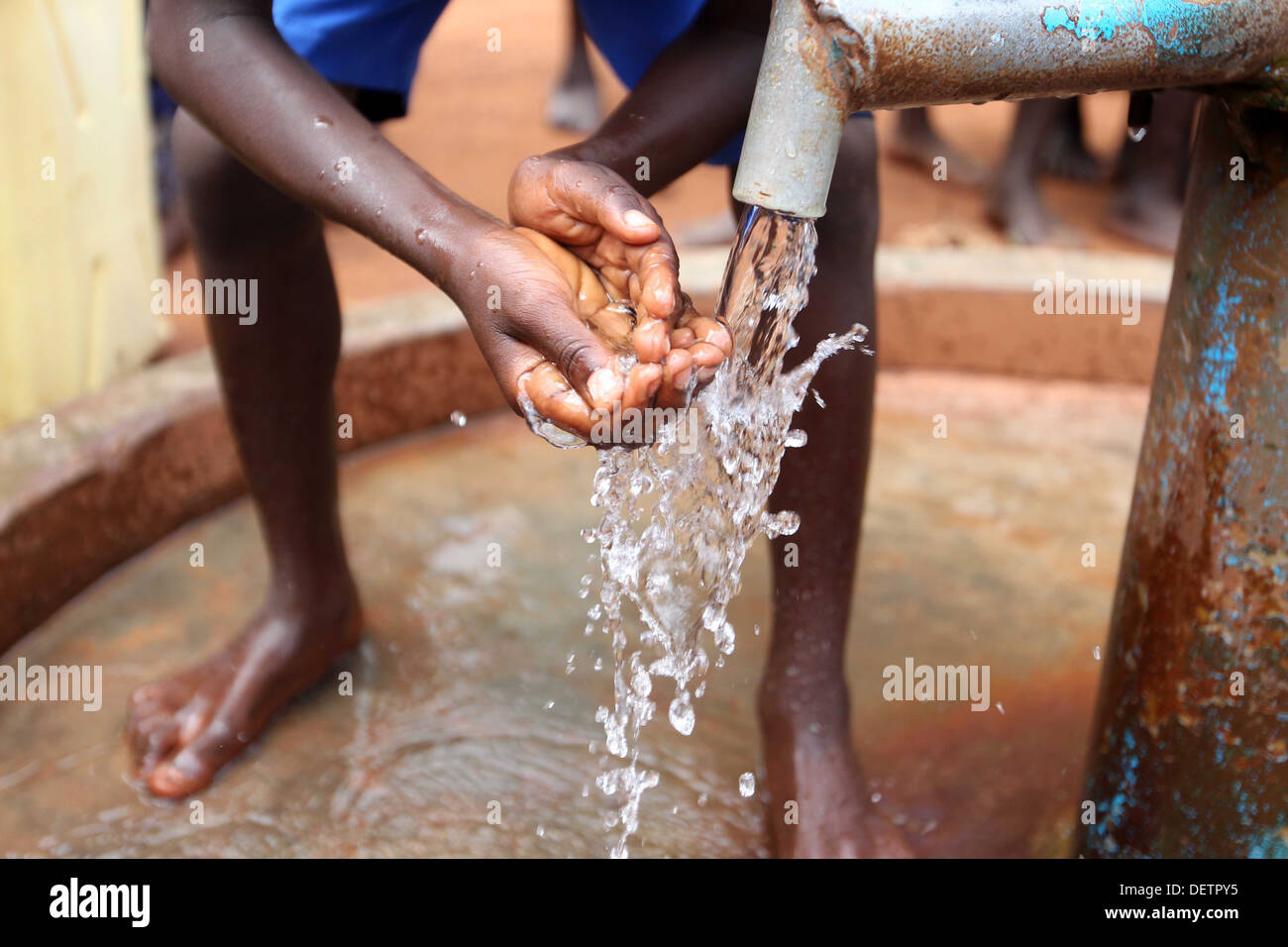 A young boy collects clean water pumped by an NGO funded well beside ...