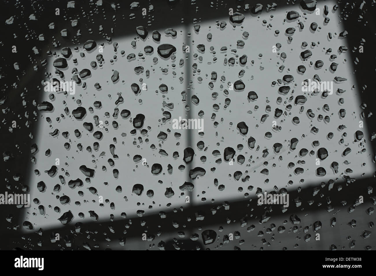 Abstract photograph of a window pane with raindrops on symbolising dull ...