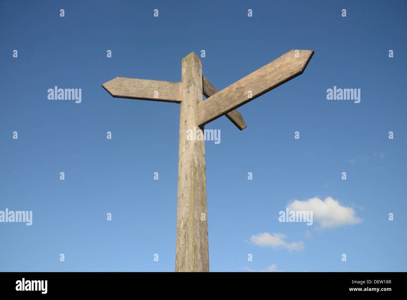 Wooden countryside signpost with blank faces. Blue sky background with ...