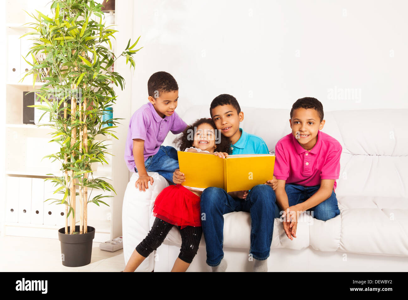 Family, group of four kids with older brother reading books to younger ...