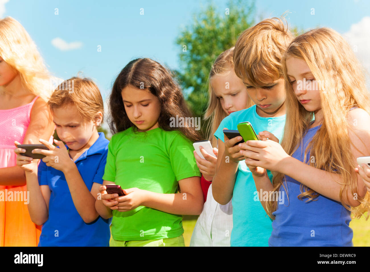 Group of busy kids looking at their phones texting sms and playing ...