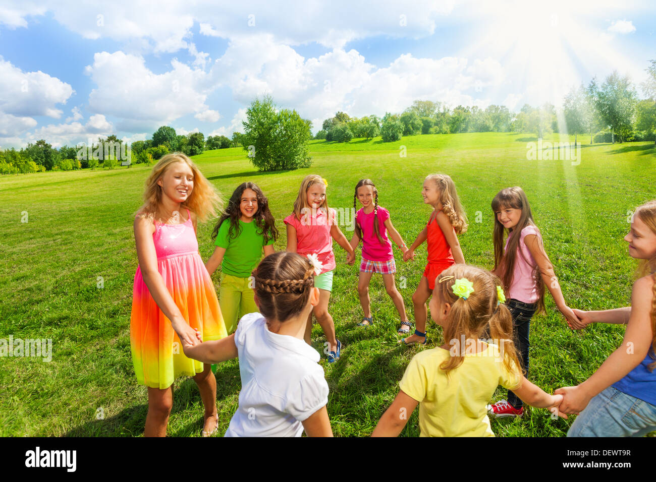 Large group of girls play roundelay and stand in circle in the park on ...