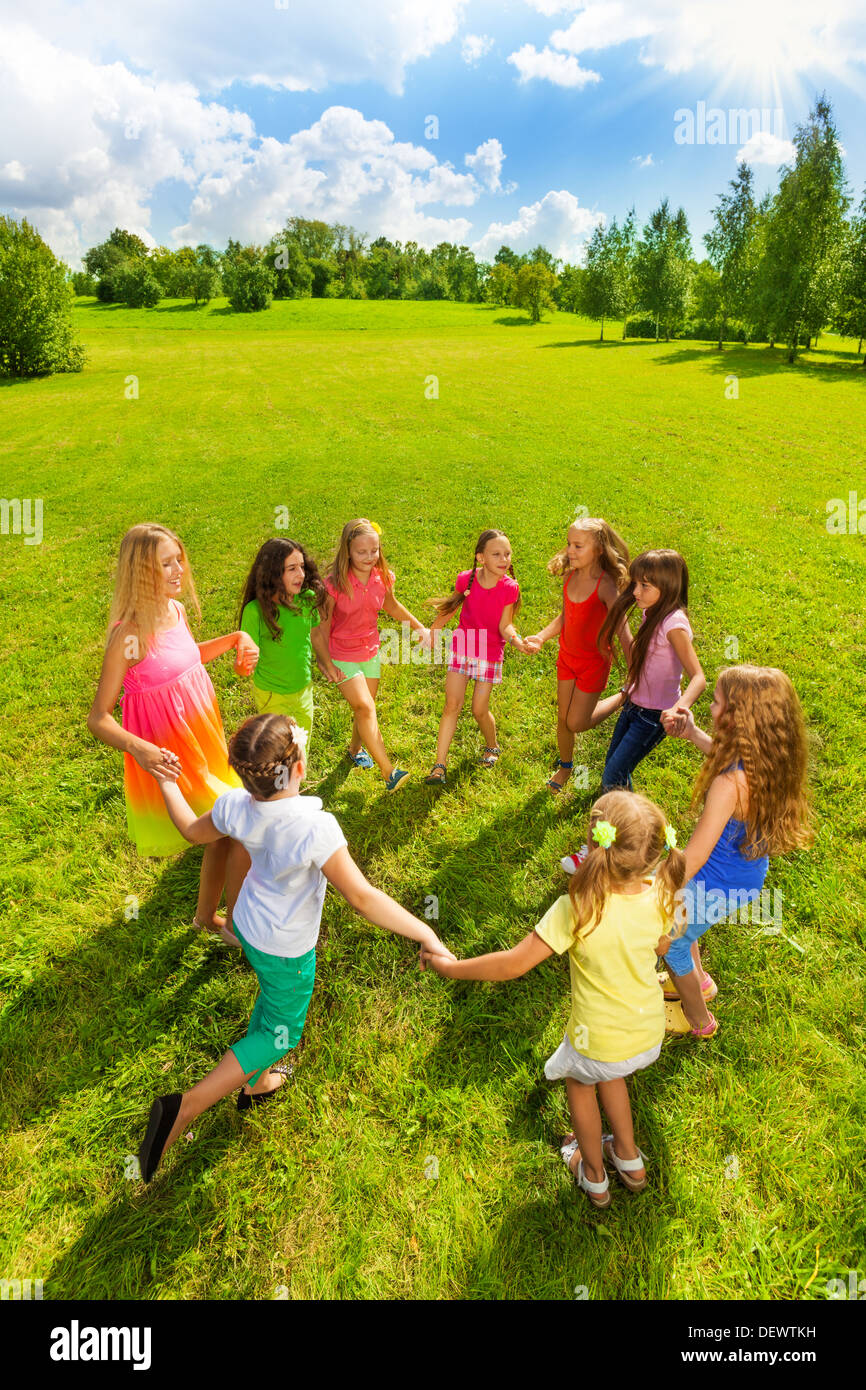 Large group of happy girls play roundelay and stand in circle in the ...