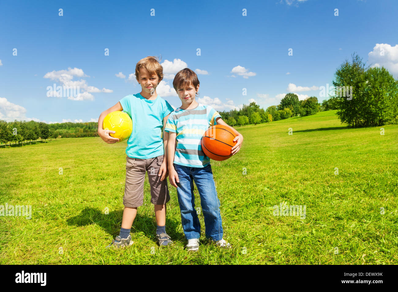 Two brothers boys kids stand with holding balls standing in the park on ...
