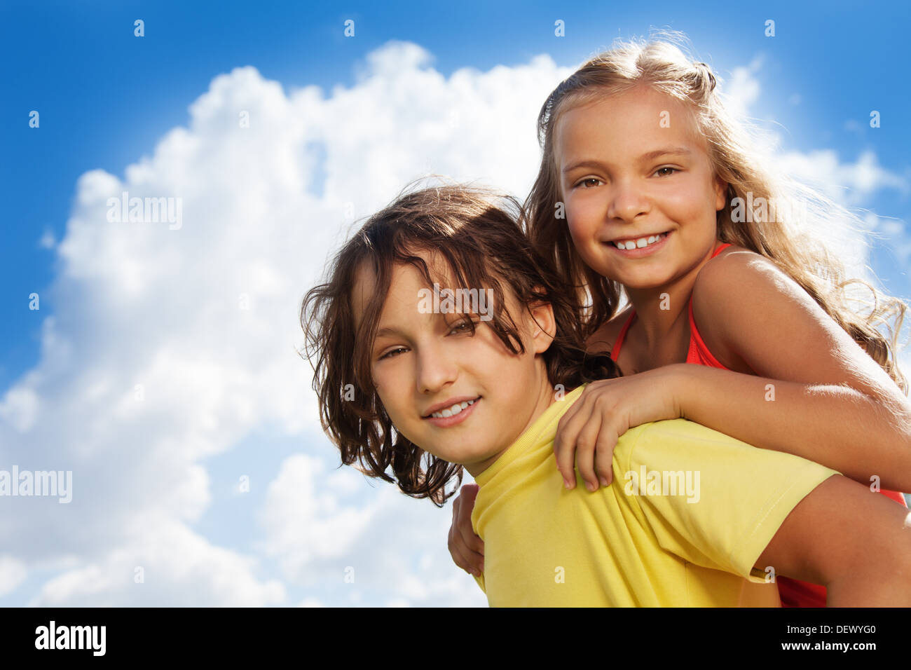 Close portrait of two school age children boy carry girl on her back ...