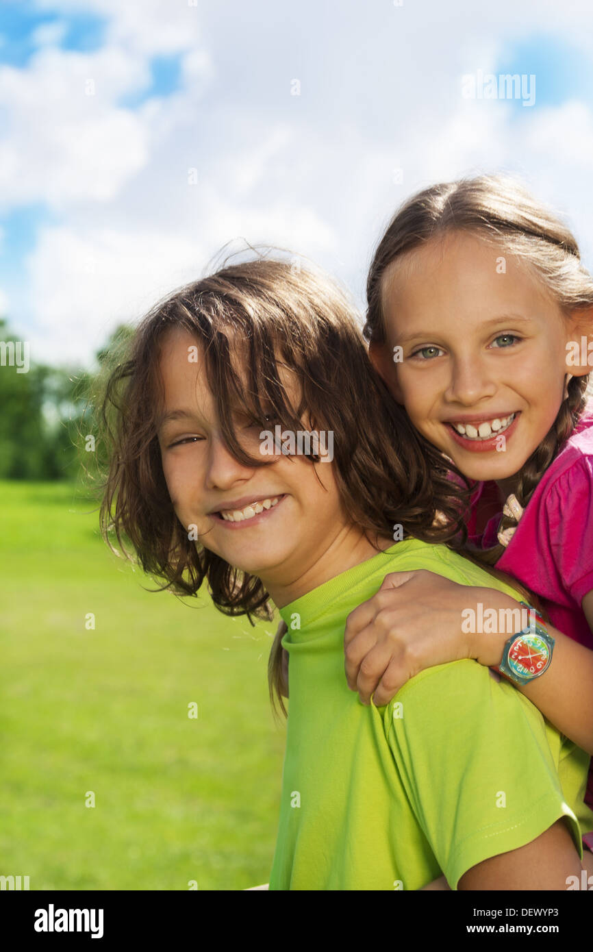 Close portrait of two kids, boy carry girl on his back, both happy and ...