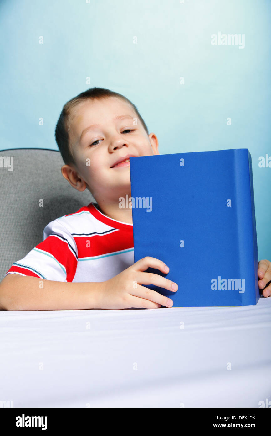 Young boy reading a book, child kid on blue background holding an open ...