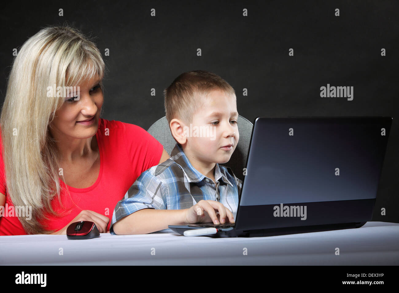 mother with son together looking on the laptop computer black ...