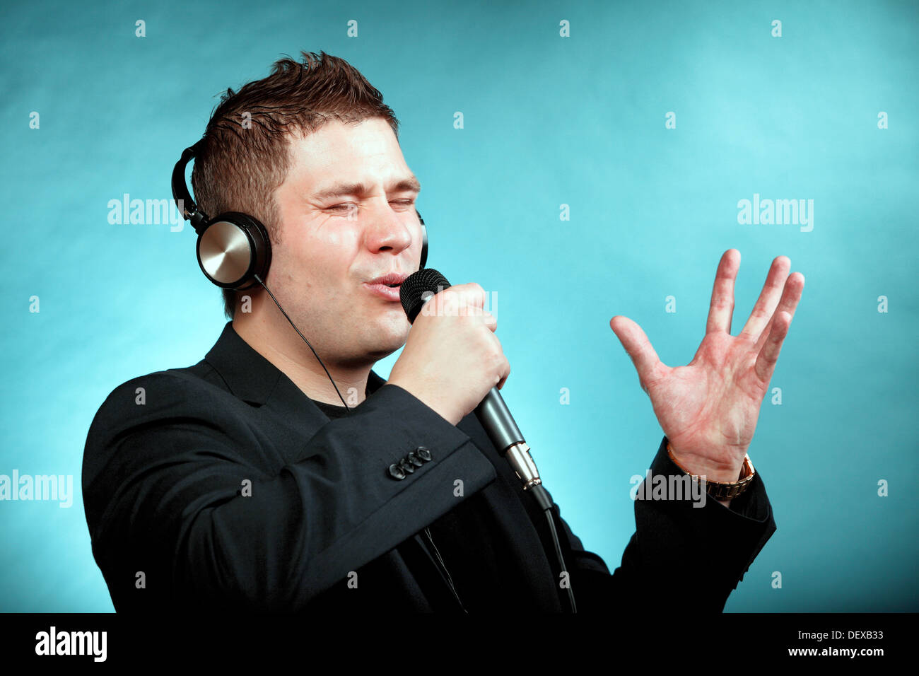 Young man singing into microphone. Happy karaoke signer studio shot ...