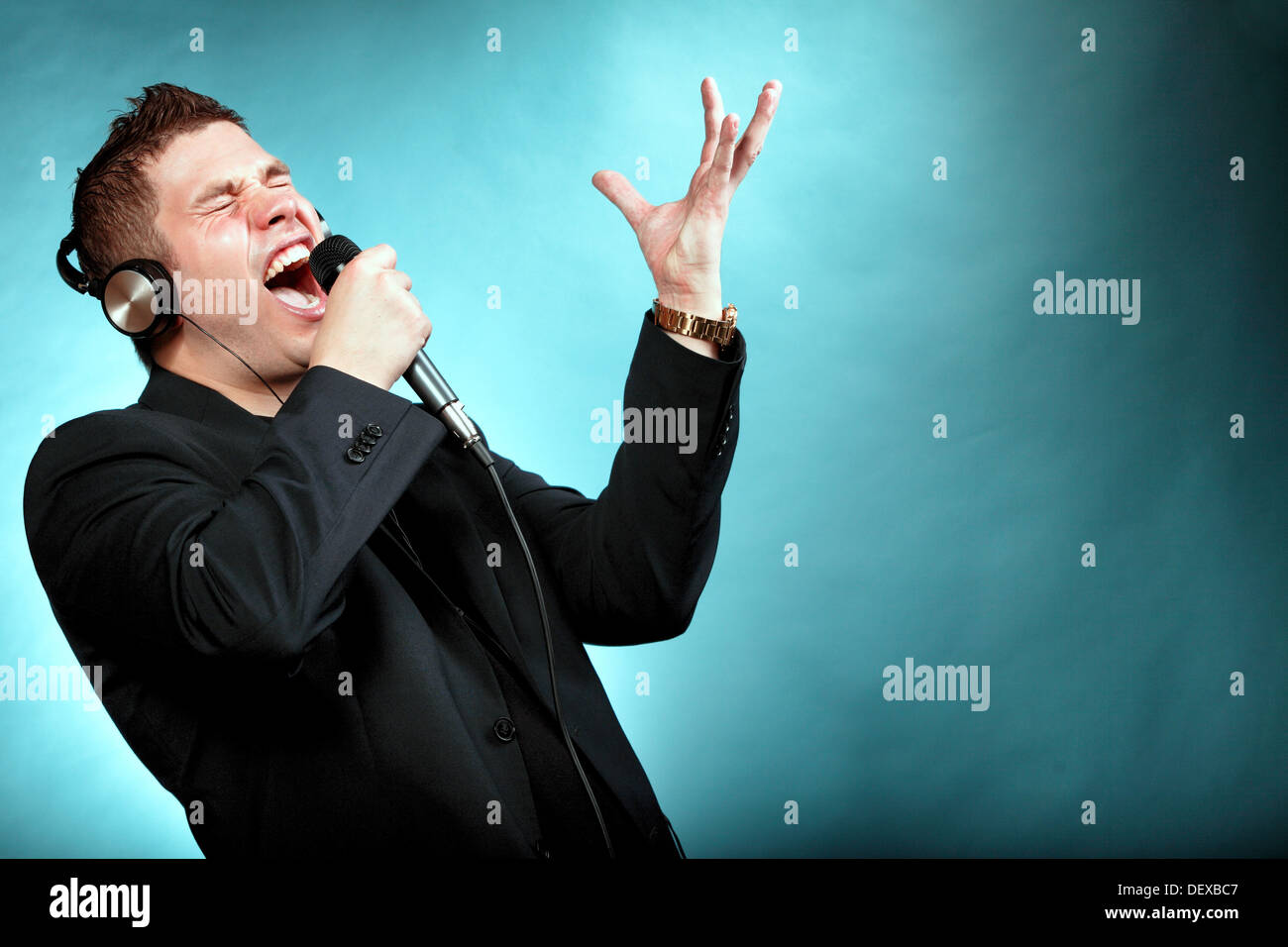 Young man singing into microphone. Happy karaoke signer studio shot ...