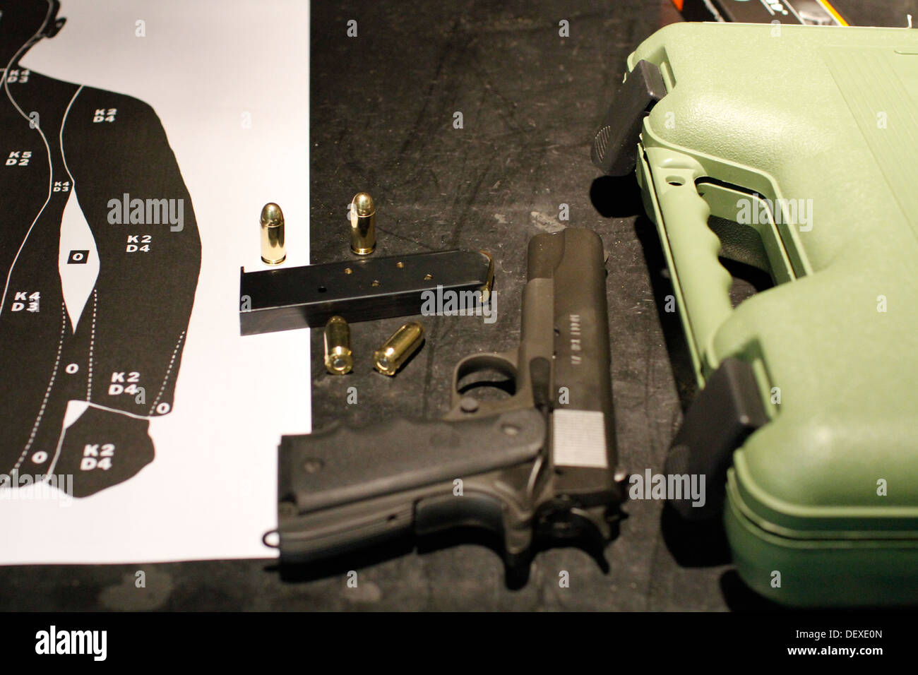 A 45 pistol sits with ammo out next to a target at an indoor gun range ...