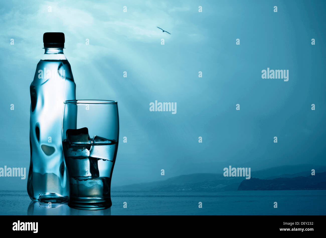 Spring mineral water bottled with glass and ice against natural marine ...