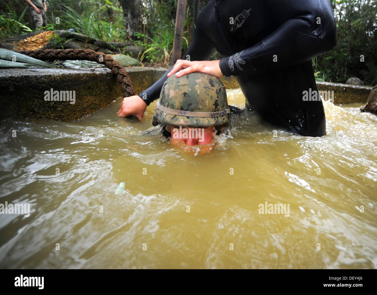 A Marine Corps Jungle Warfare Training Center (JWTC) Instructor helps ...