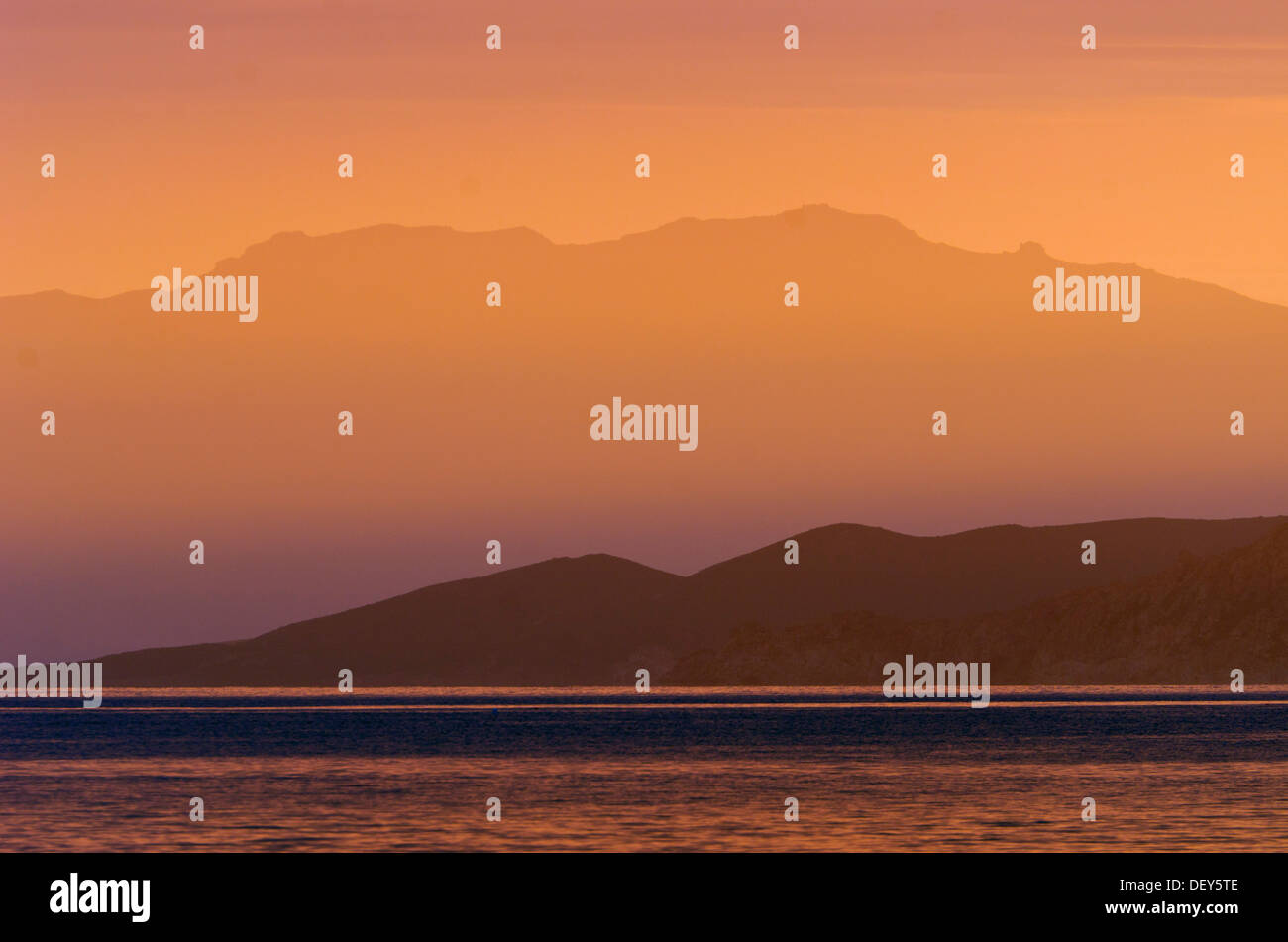 The rising sun forms sun beams behind the rocks of the island Ile de la ...