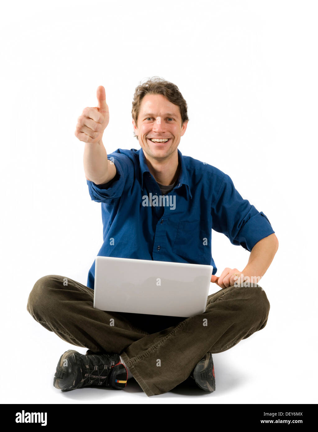 Man sitting cross-legged on floor with a laptop, making thumbs up ...